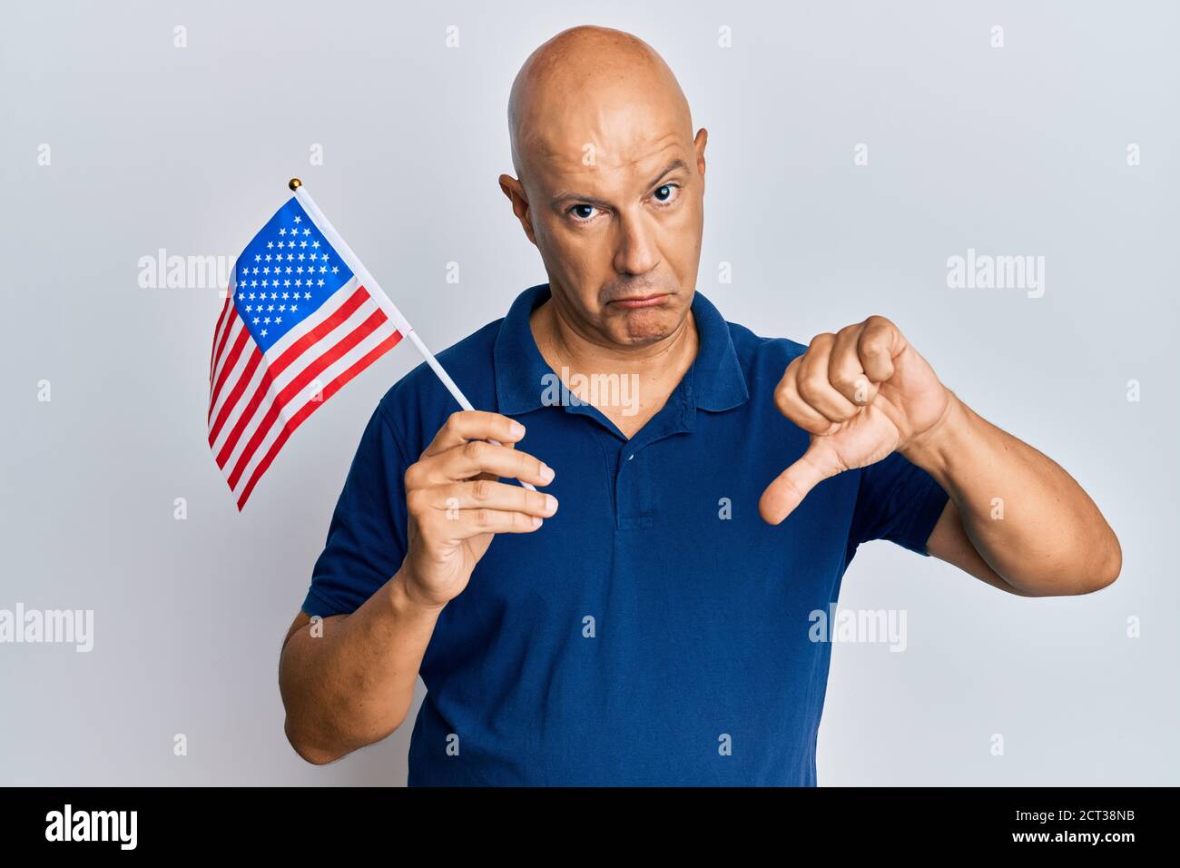 Middle age bald man holding united states flag with angry face ...