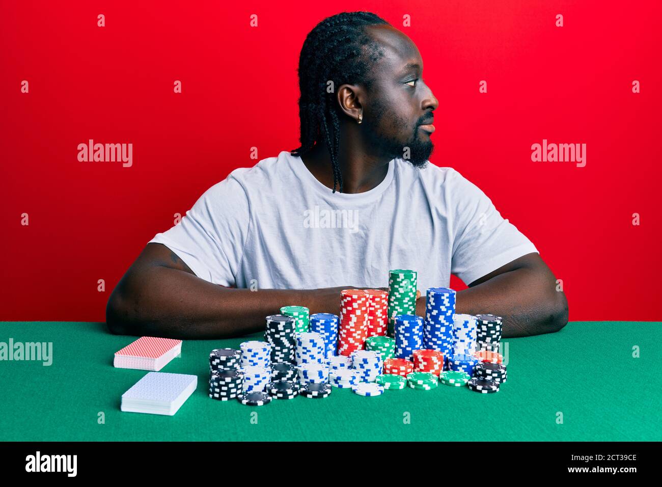 Handsome young black man sitting on the table with poker chips and ...
