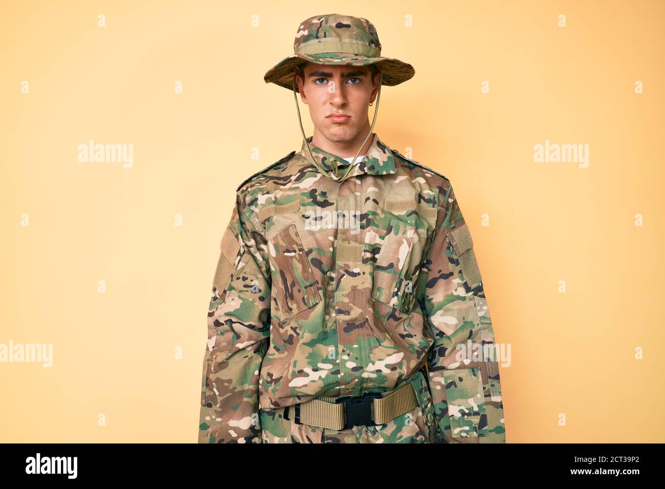 Young handsome man wearing camouflage army uniform depressed and worry ...