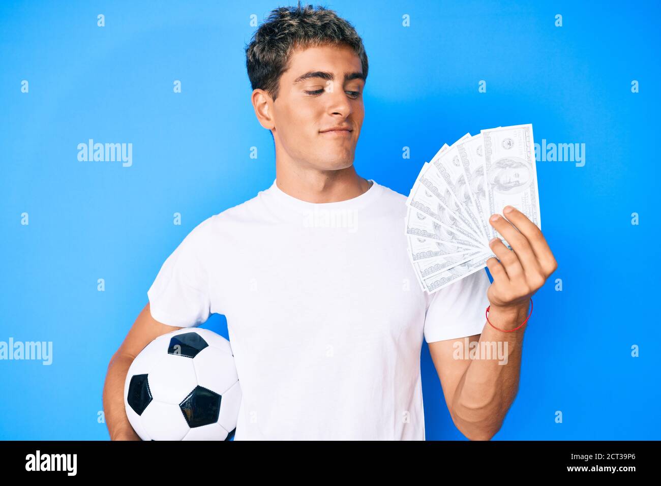 Young handsome man holding soccer ball and dollars banknotes smiling ...
