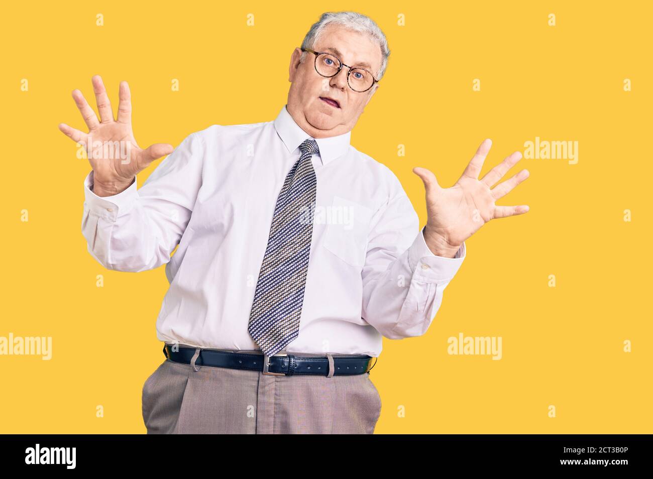 Senior grey-haired man wearing business clothes afraid and terrified ...