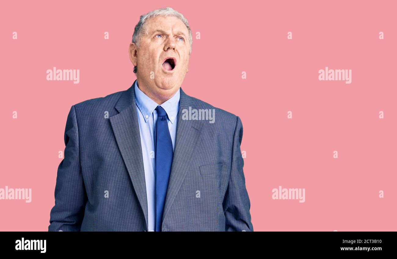 Senior grey-haired man wearing business jacket angry and mad screaming ...