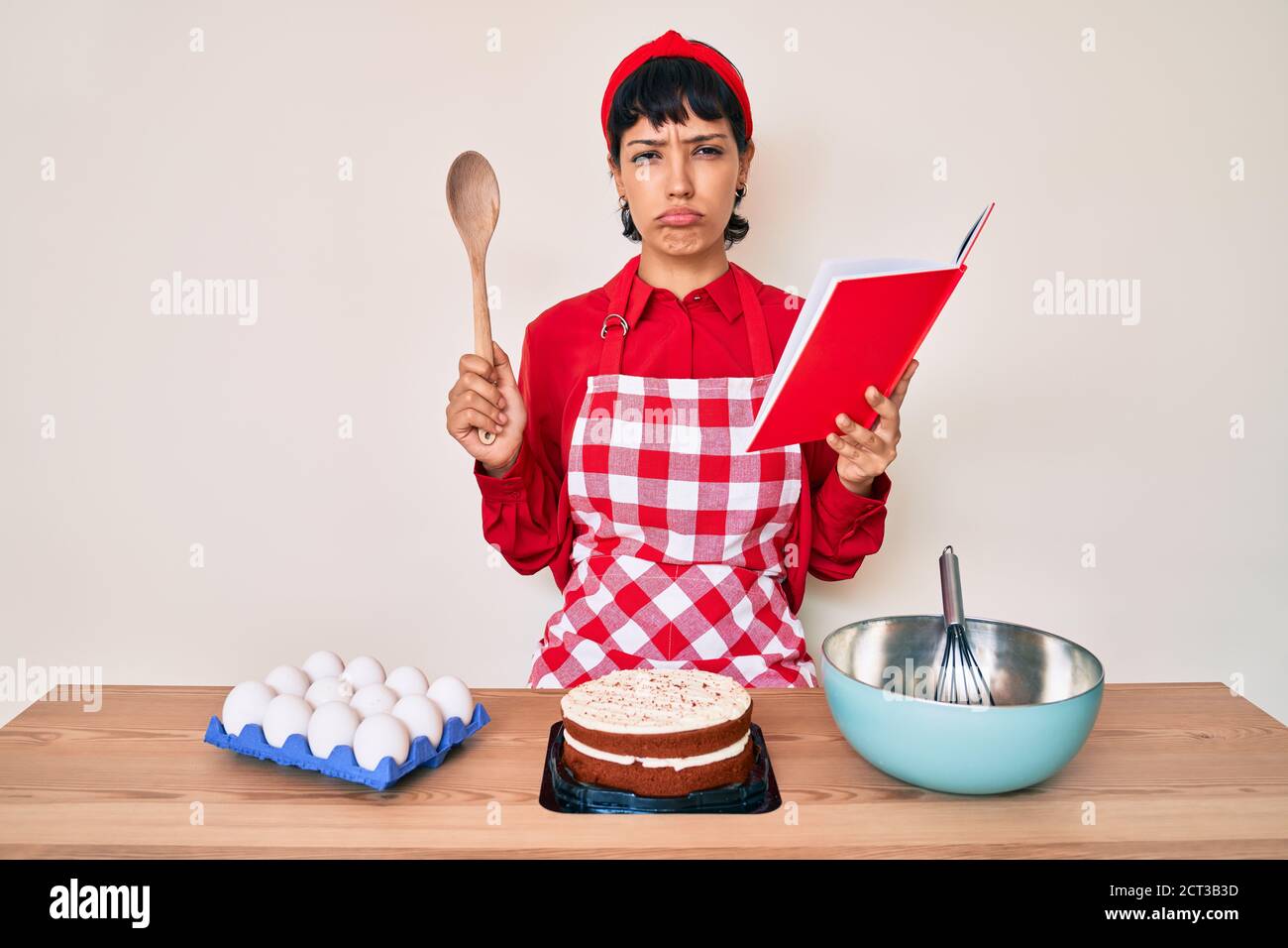 Beautiful brunettte woman cooking cake reading recipes book depressed ...
