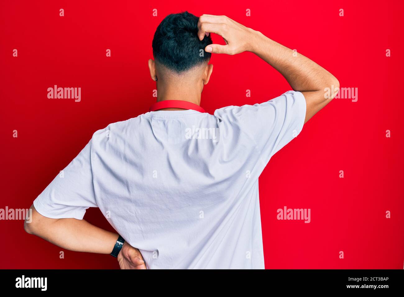 Young man with beard listening to music using headphones backwards ...