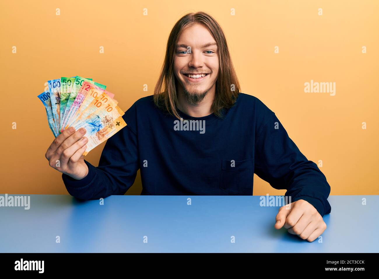 Handsome caucasian man with long hair holding swiss franc banknotes ...