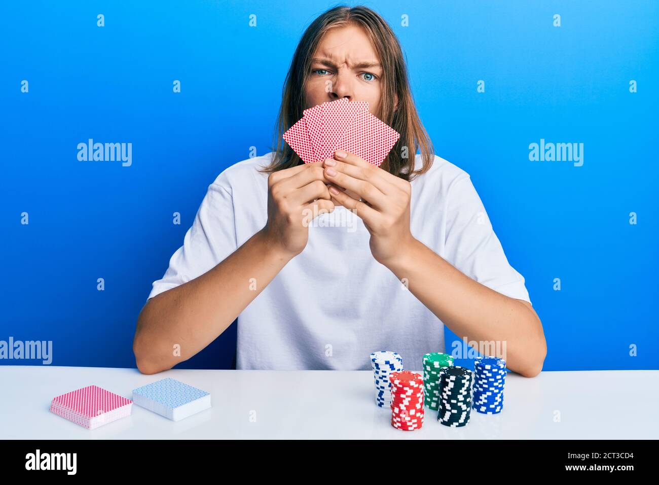 Handsome caucasian man with long hair playing gambling poker covering ...