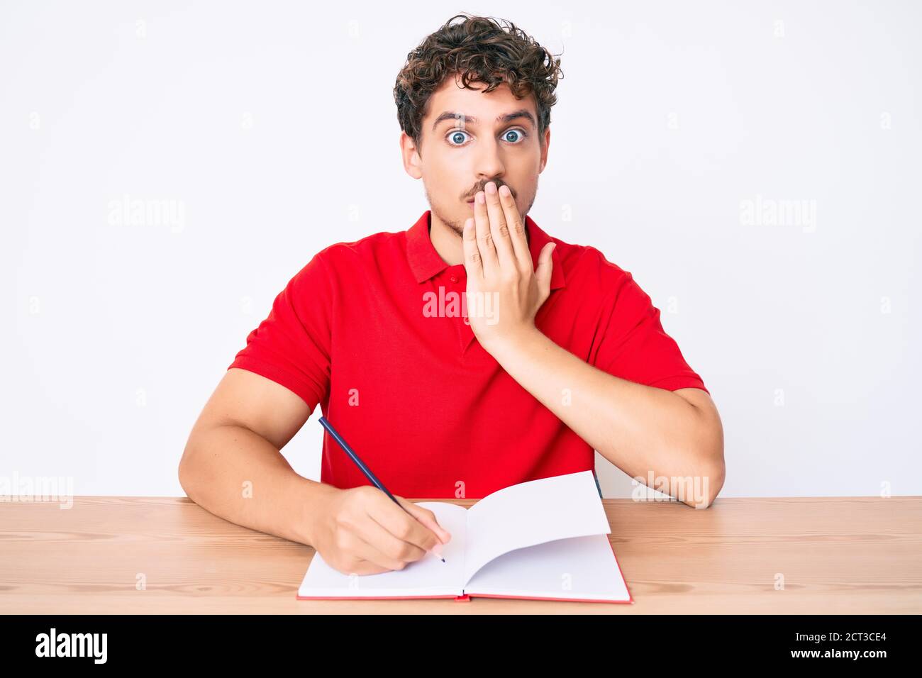 Young caucasian man with curly hair writing notebook sitting on the ...