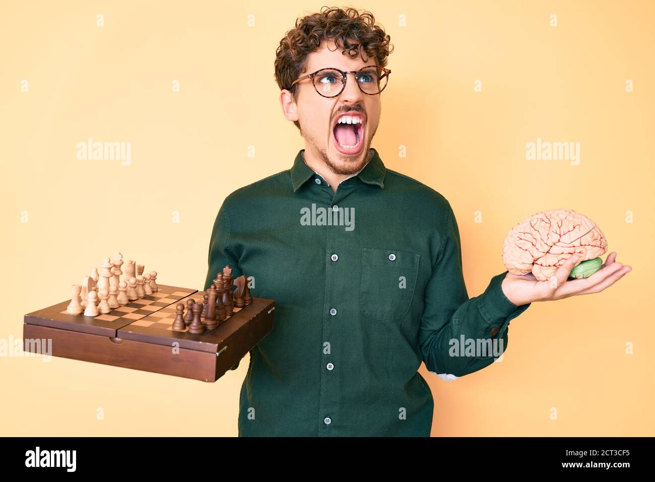 Young caucasian man with curly hair holding brain while playing chess ...