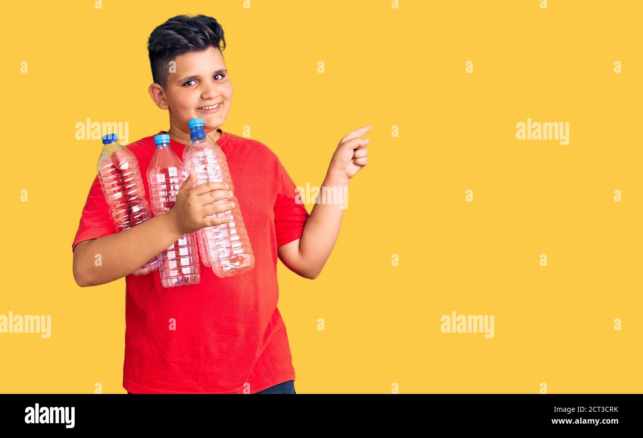 Little boy kid holding recycling plastic bottles smiling happy pointing ...
