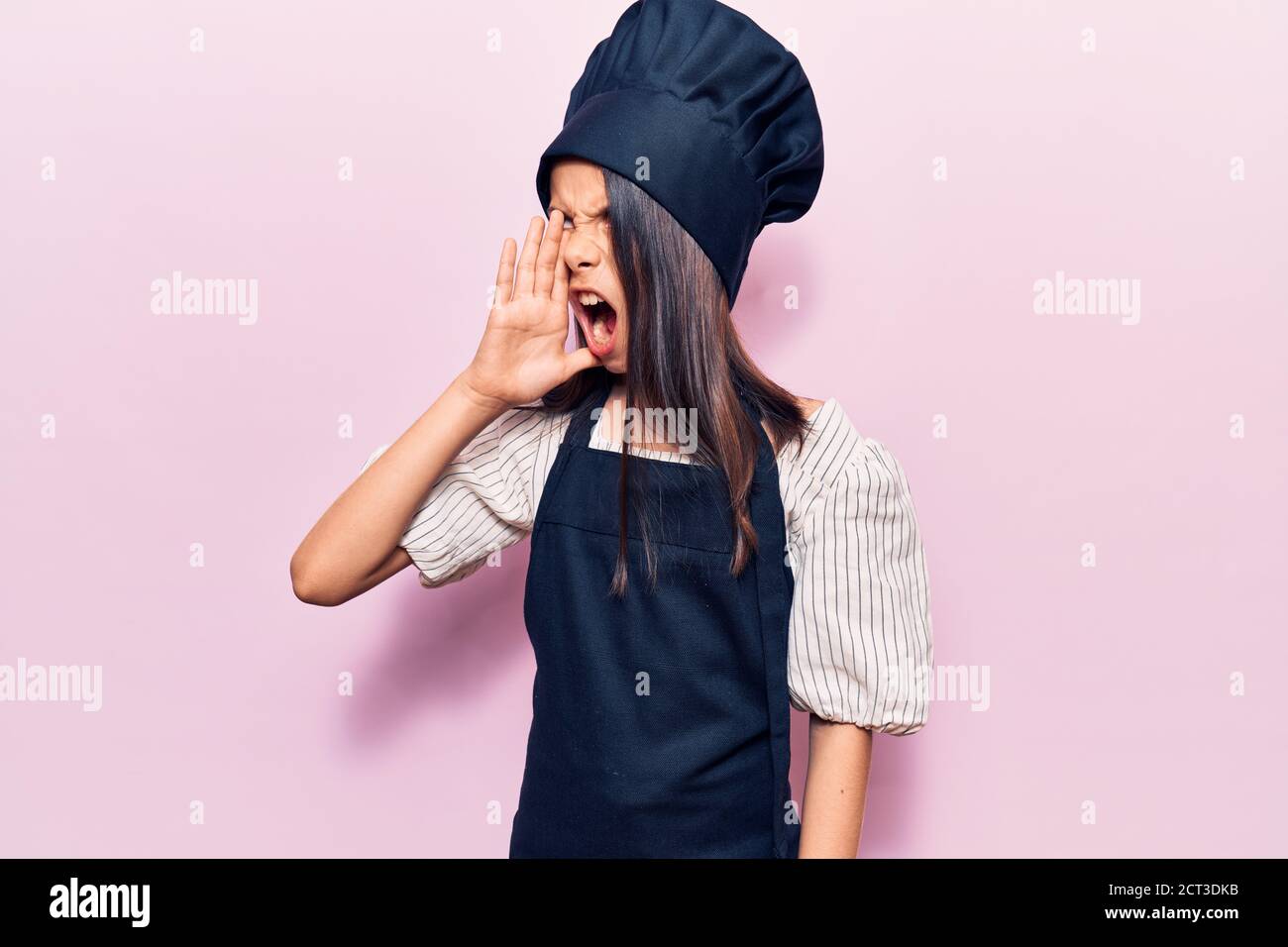 Beautiful child girl wearing cooker uniform shouting and screaming loud ...