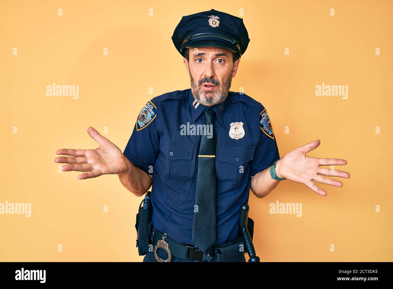 Middle age hispanic man wearing police uniform clueless and confused ...