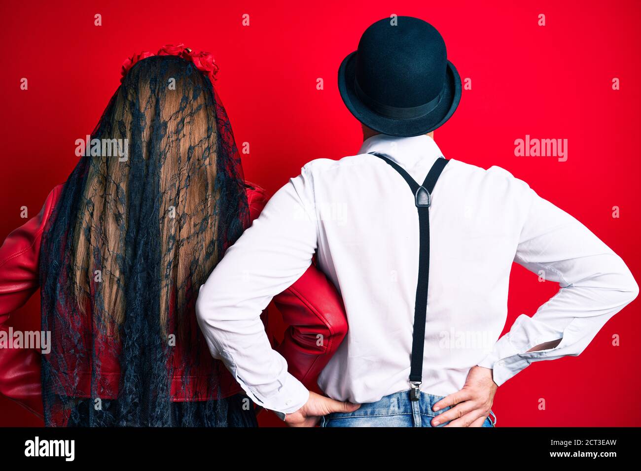 Couple wearing day of the dead costume over red standing backwards ...
