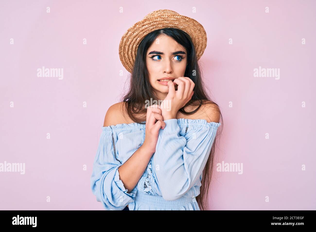 Brunette teenager girl wearing summer hat looking stressed and nervous ...