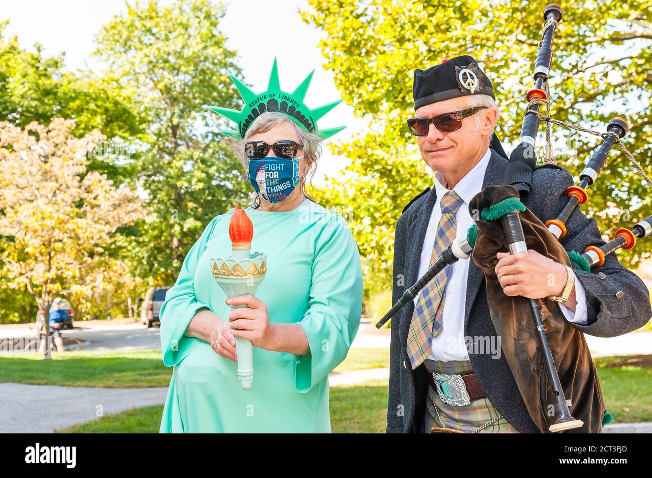 Woman dressed as the Statue of Liberty standing with a bagpiper at the ...