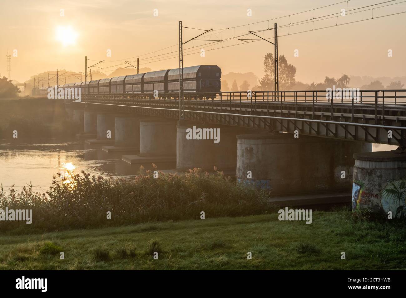Train going over a bridge at sunrise Stock Photo - Alamy
