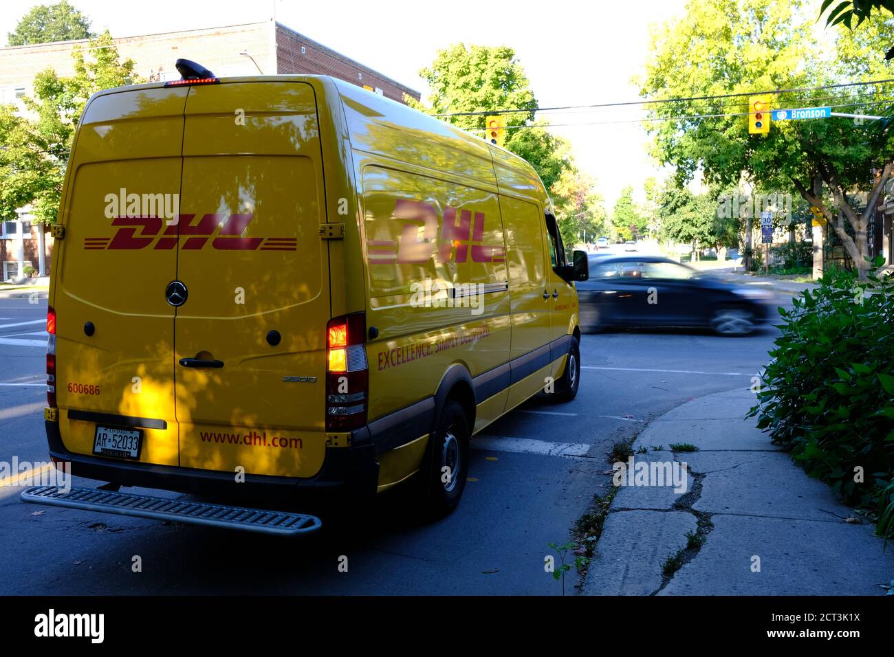 Bright yellow DHL delivery van waiting to turn right on to Bronson Ave ...