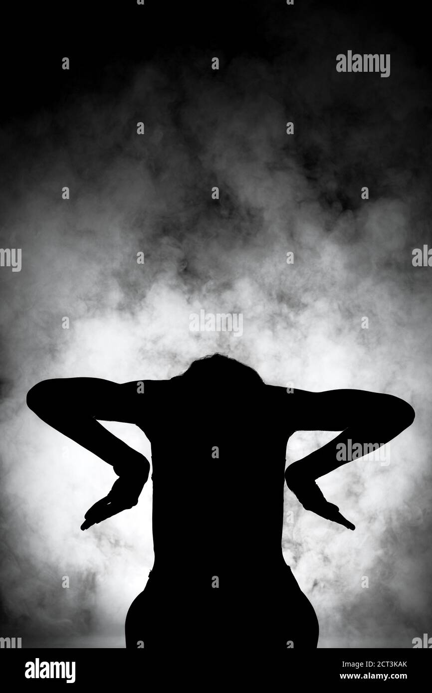 silhouette modern ballet dancer posing on dark background with smoke ...