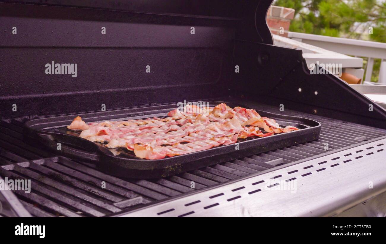 Cooking bacon stips on an outdoor gas grill Stock Photo - Alamy