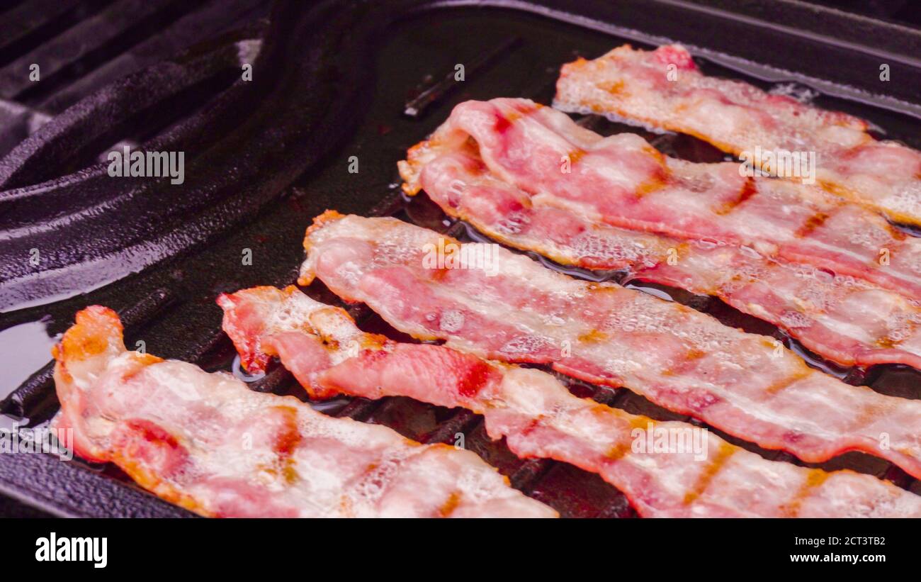 Cooking bacon stips on an outdoor gas grill Stock Photo - Alamy