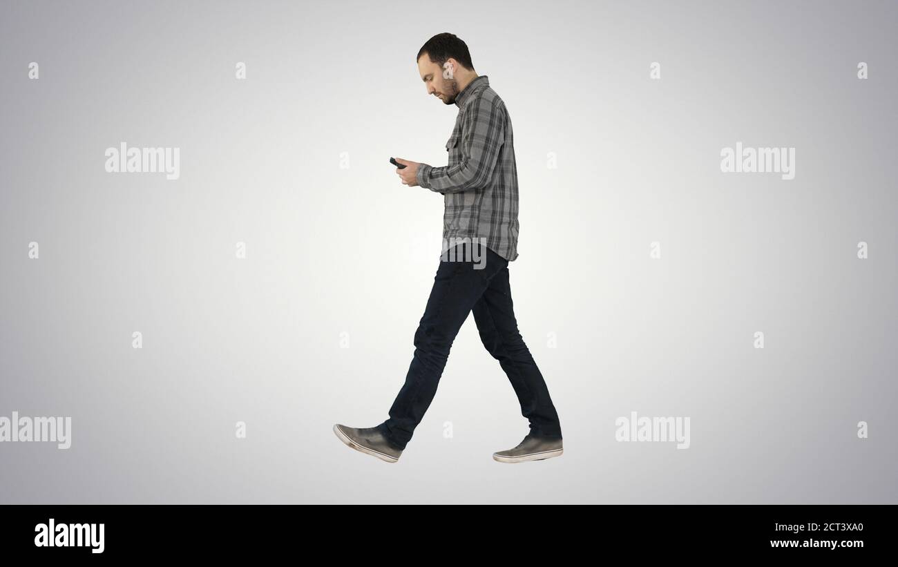 Young smart casual man walking and reading message on cell phone Stock ...