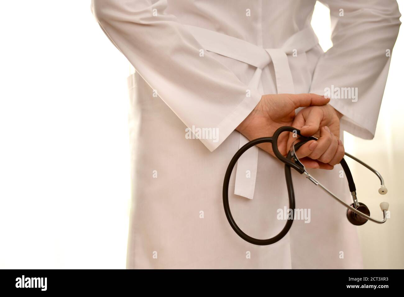 The doctor in a white robe facing the light, hands with a stethoscope ...