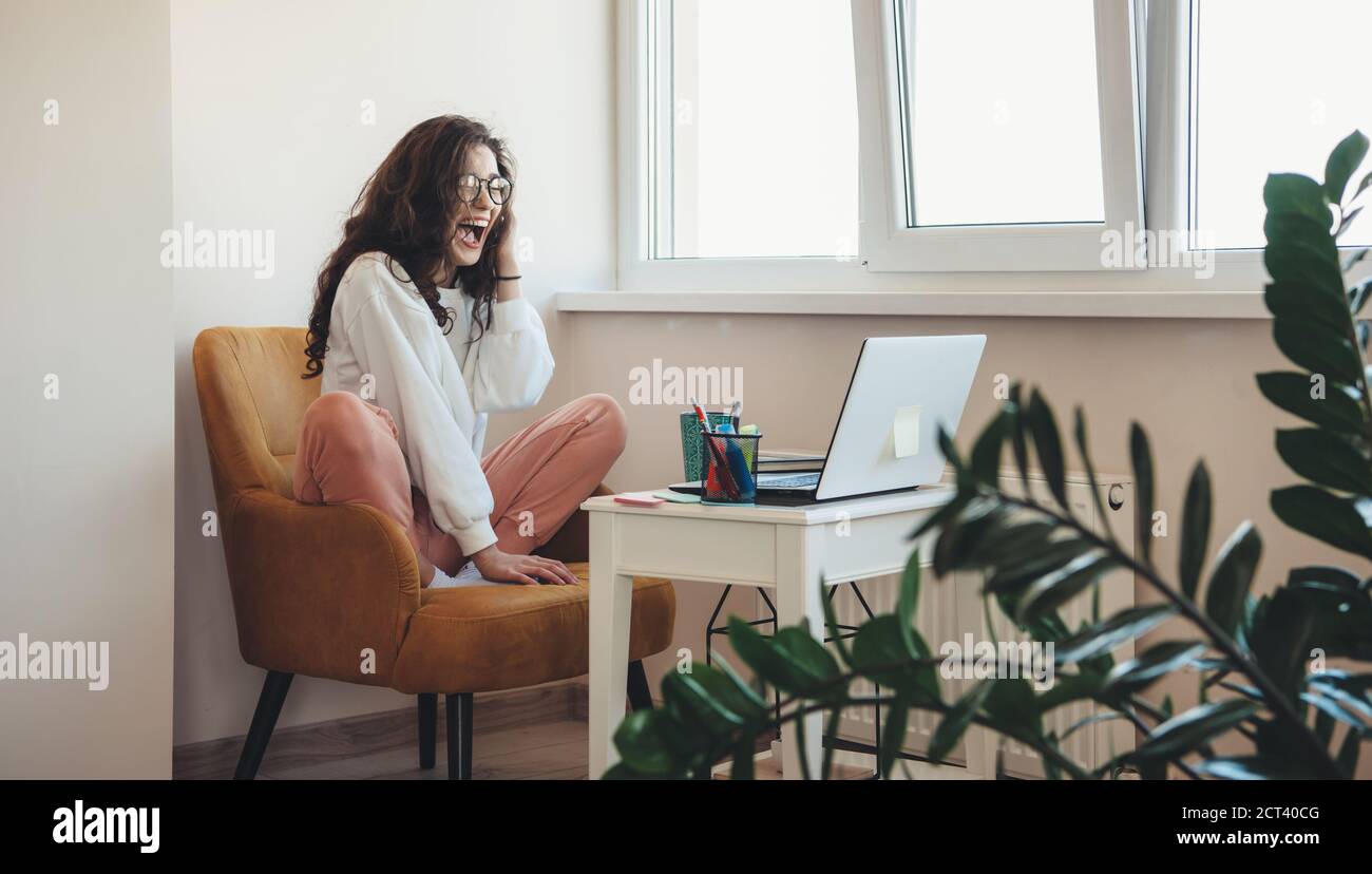Excited caucasian woman screaming while talking with somebody on laptop ...