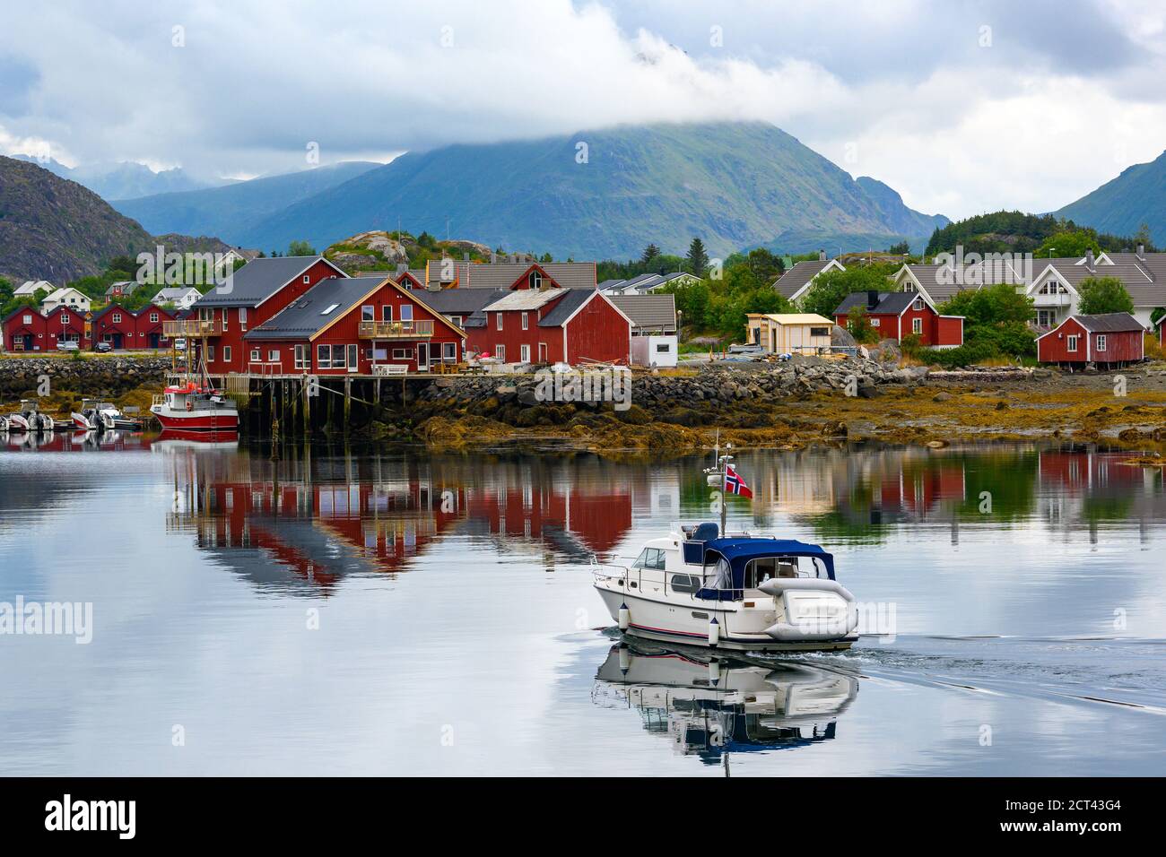 A tourist boat runs on the water at Ballstad Lofoten Island, Norway ...