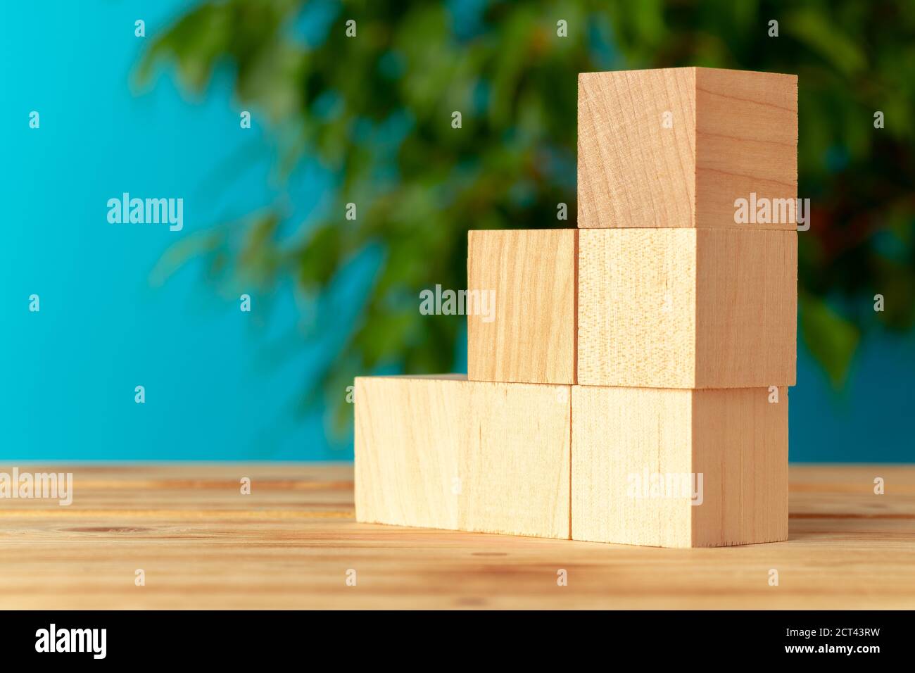 Wooden blocks on desk against blurred plant background Stock Photo - Alamy