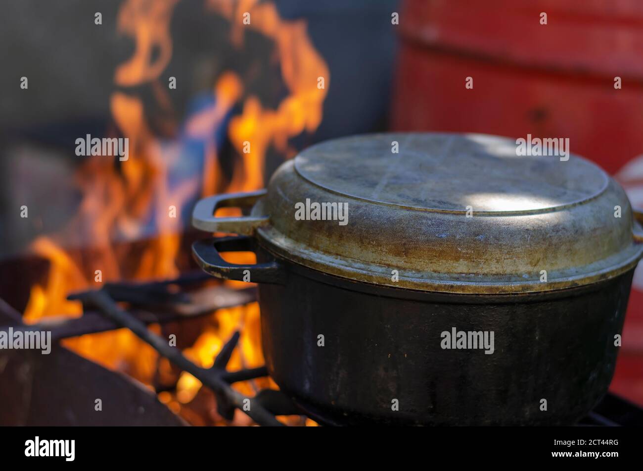 Cast iron cauldron with a lid on fire. Cooking food over the fire ...