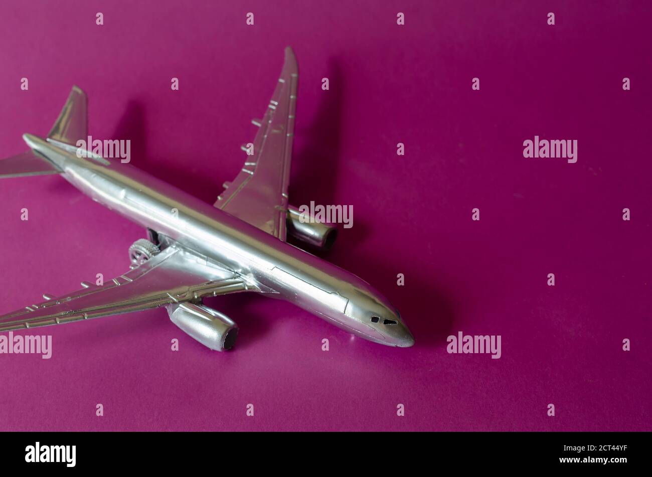 Model of a passenger plane in on a pink background. Silver plane close ...