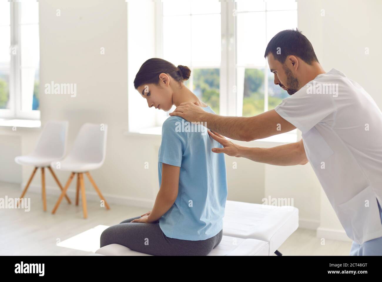 Licensed doctor helping young woman to ease back pains in modern ...