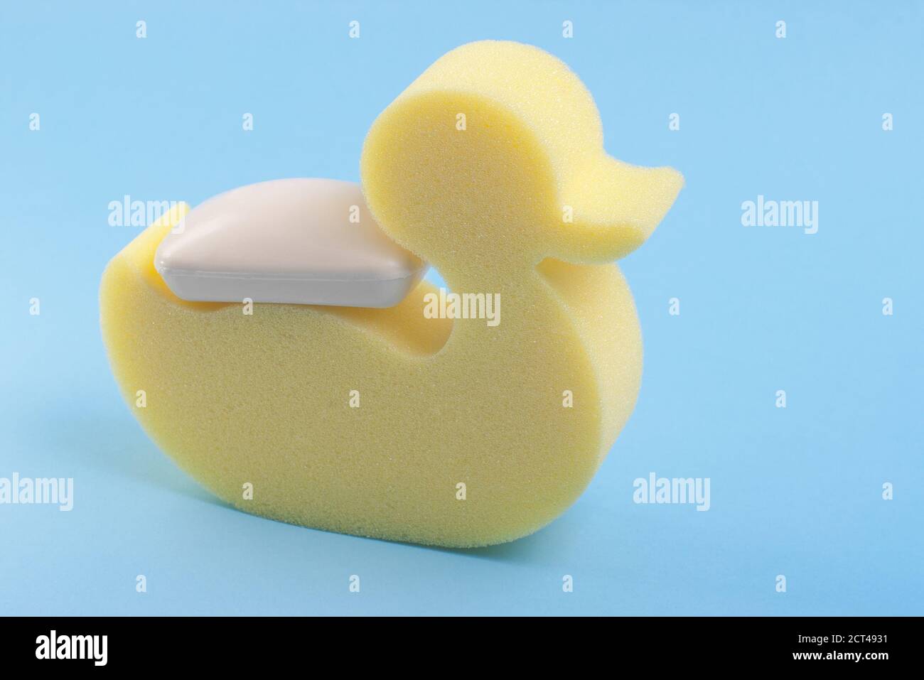 Yellow duck sponge carrying soap bar against light blue background ...