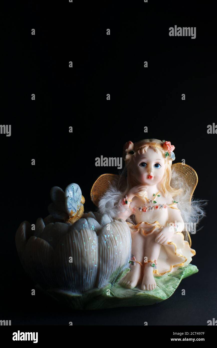 Figurine of a little angel girl from gypsum sitting against black ...