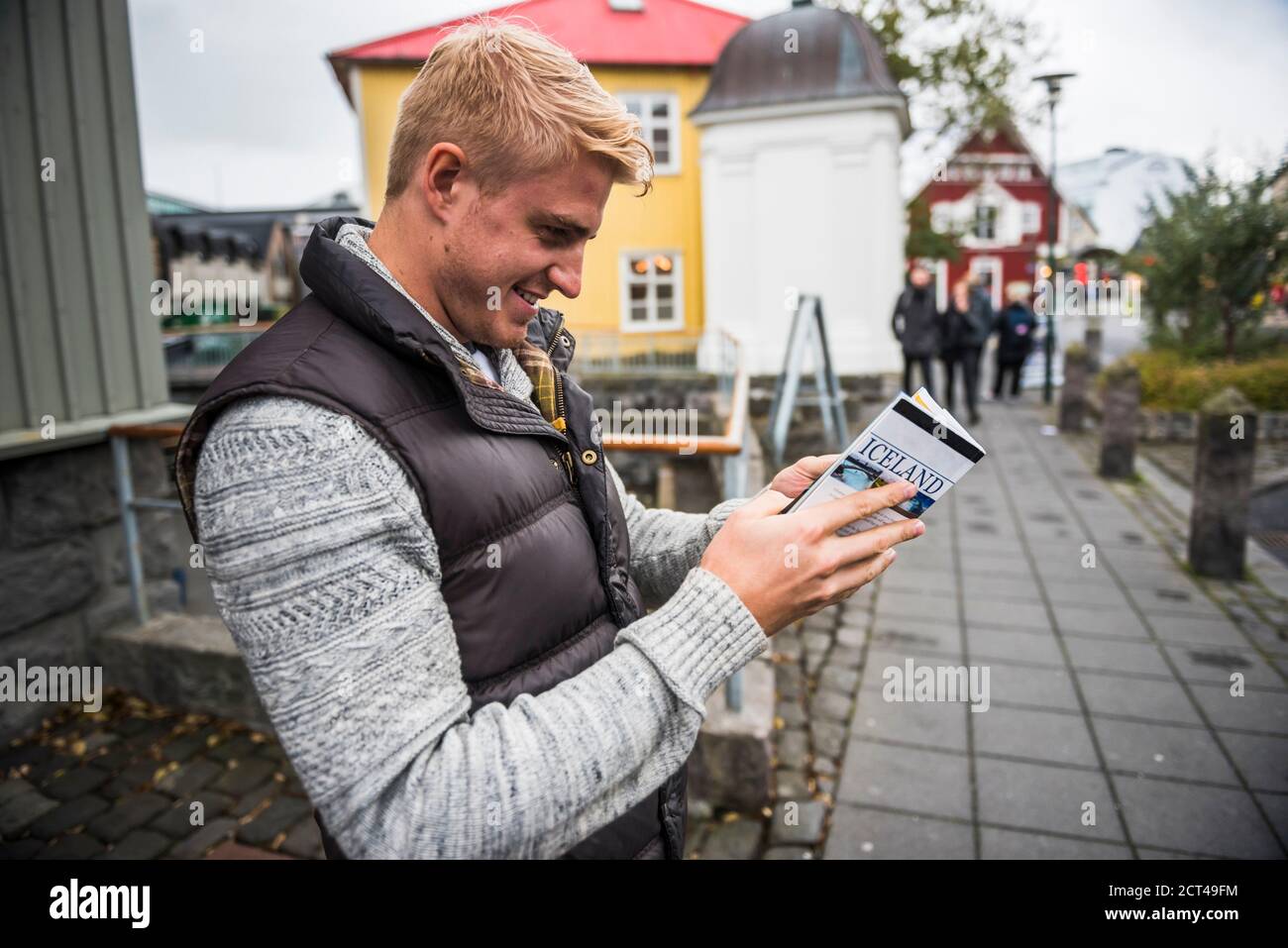 Young tourist man sightseeing in Reykjavik old town looking through a ...