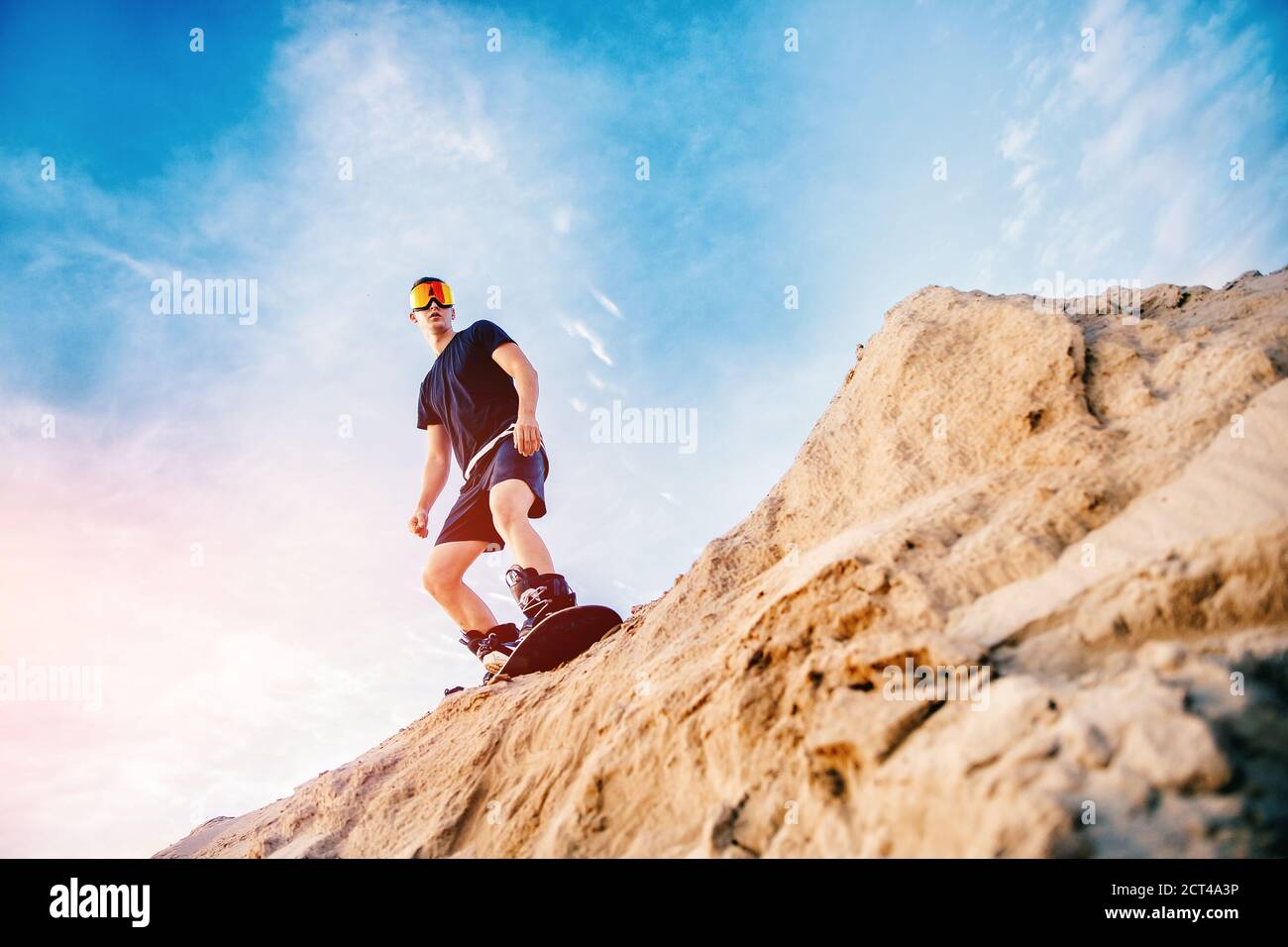 Extreme descent sand on snowboard in desert. Male snowboarder on dunes ...