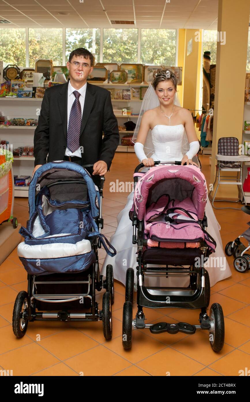 Smiling couple of newlyweds with empty baby carriages in store Stock ...