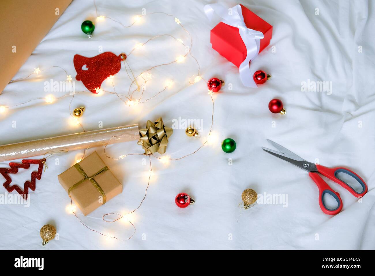 Christmas gifts wrapping, paper, scissors and accessories on white bed ...