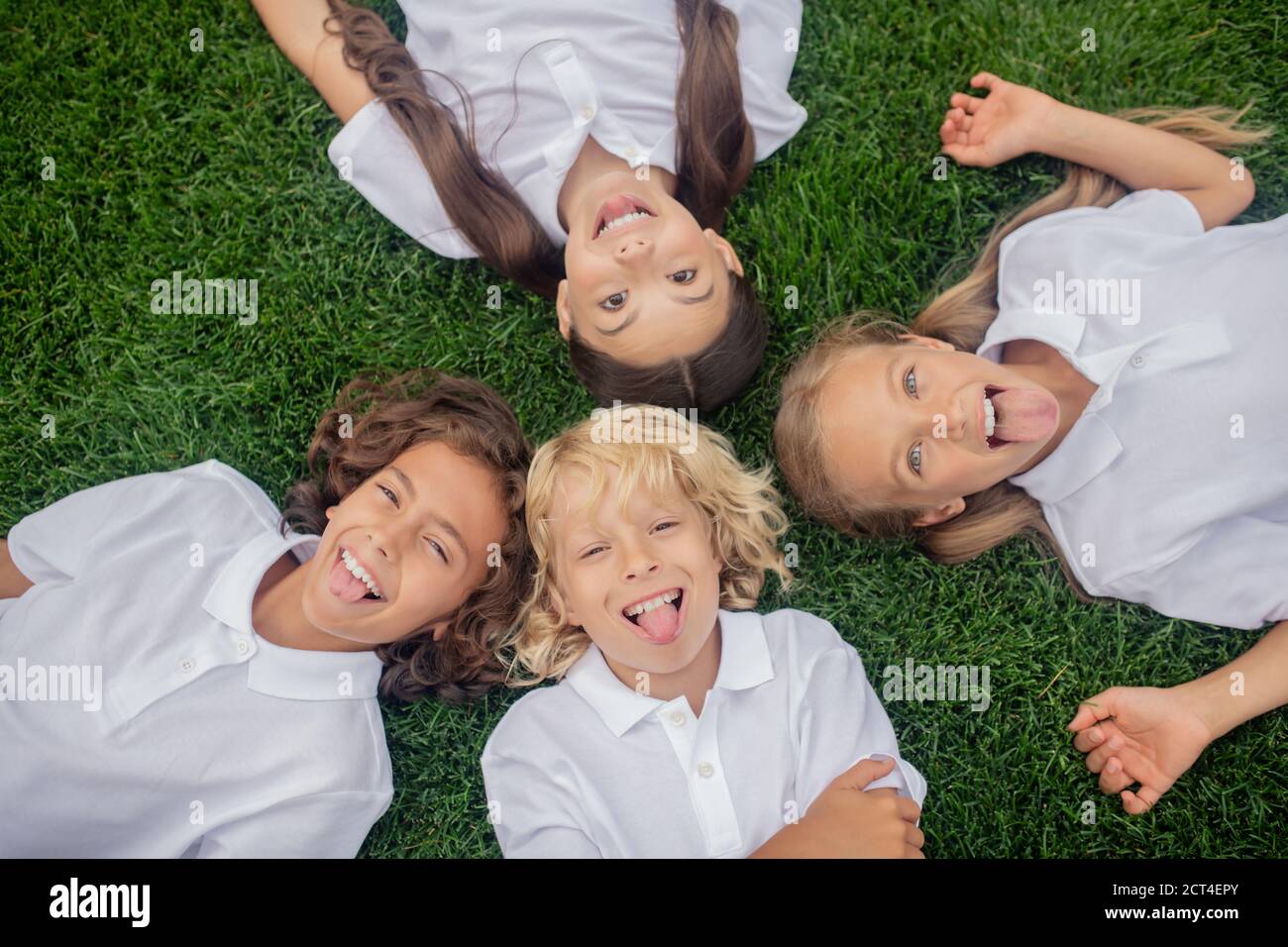 Children in white lying on the grass and smiling Stock Photo - Alamy