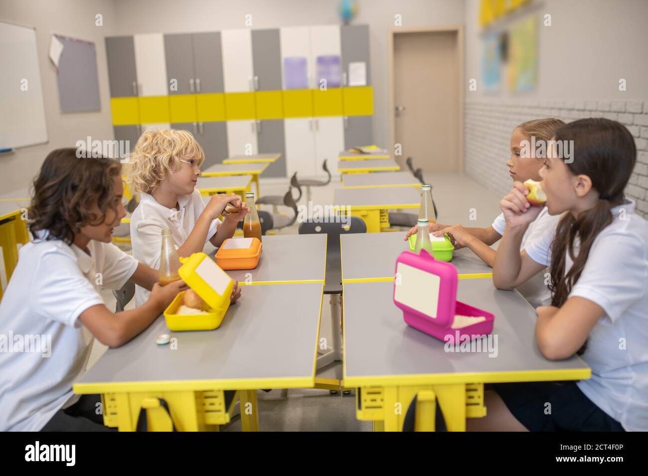 Schoolchildren having lunch in the classroom and talking Stock Photo ...