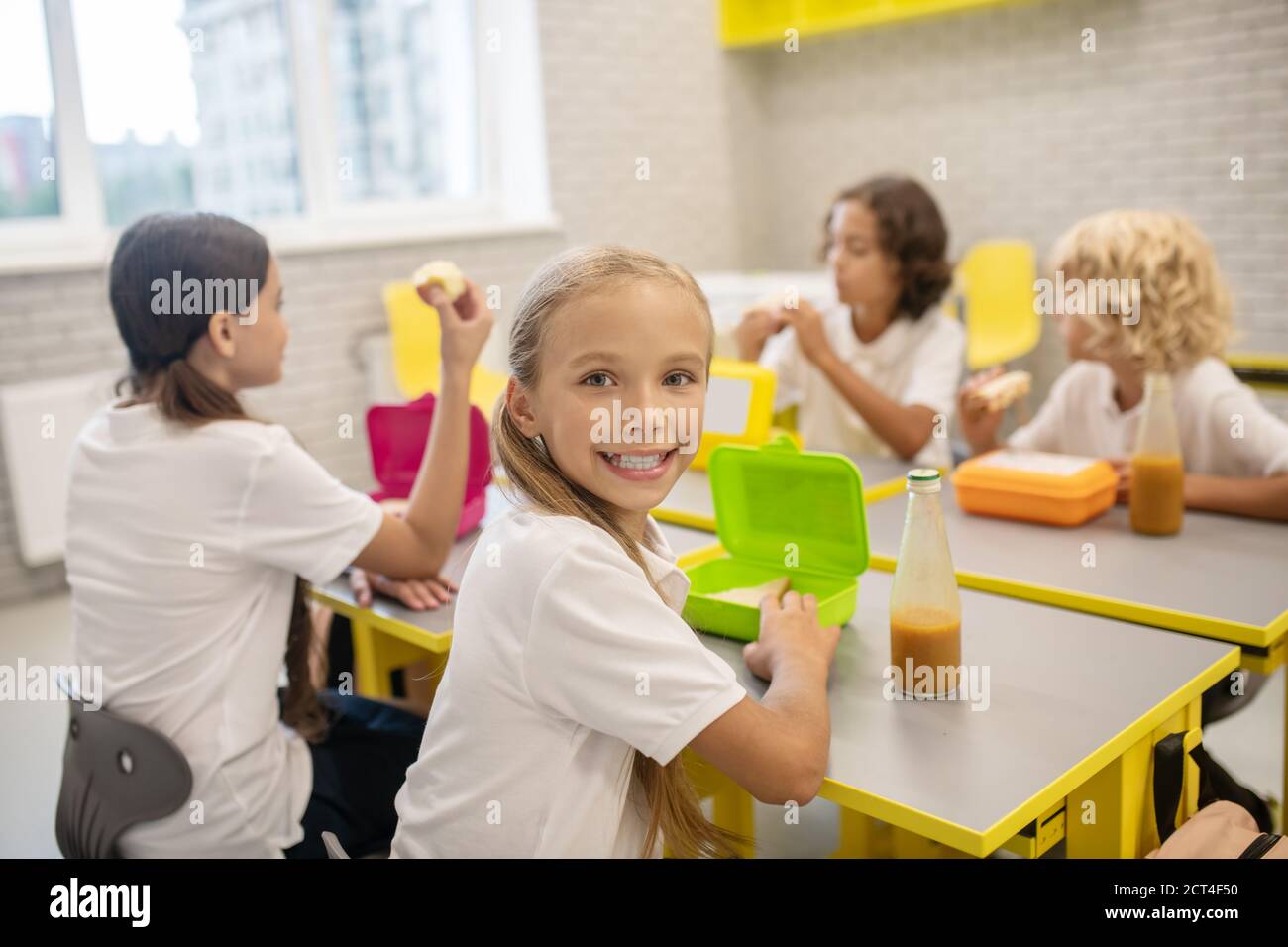 Schoolchildren having lunch in the classrom and looking excited Stock ...