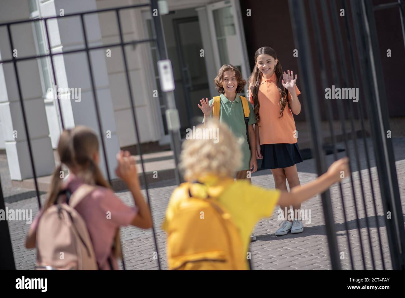 Schoolchildren leaving school after the lessons and waiting for friends ...