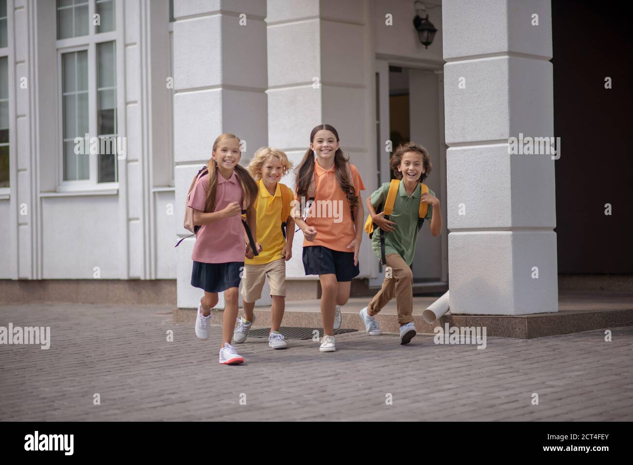 Schoolchildren running happily while leaving school after lessons Stock ...