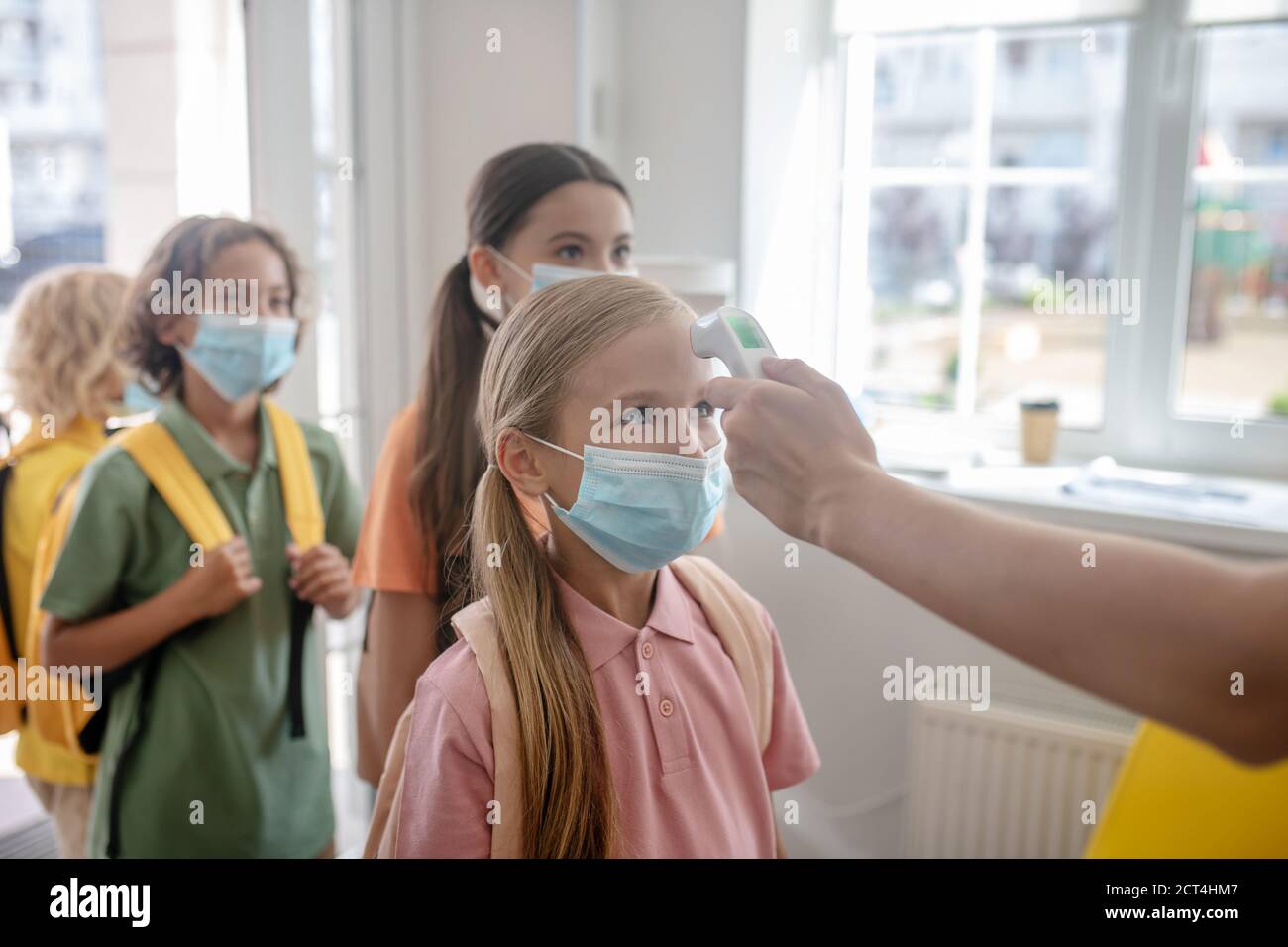Schoolchildren passing temperature control while entering the school ...
