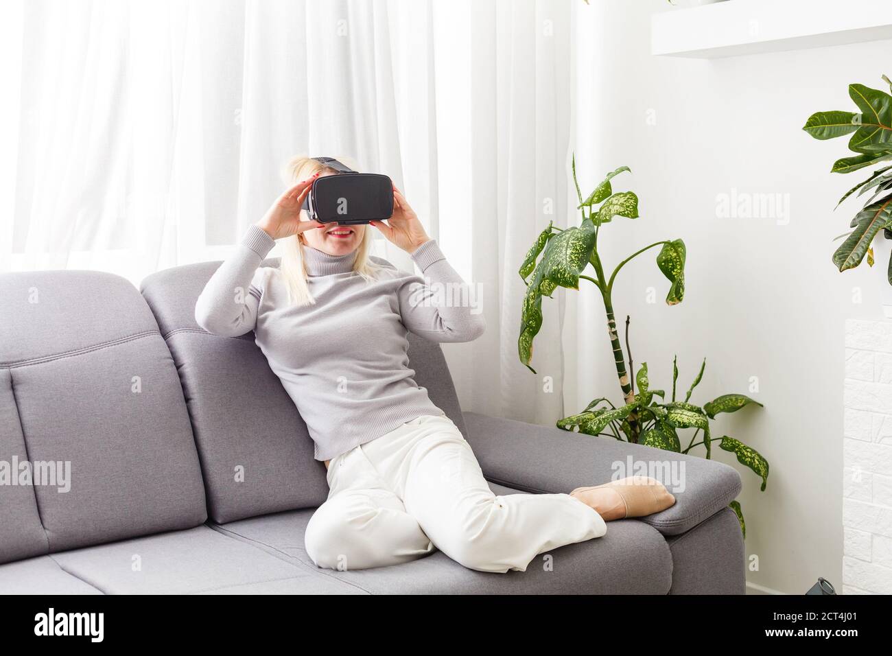 Future is now. Attractive young woman adjusting her VR headset and ...
