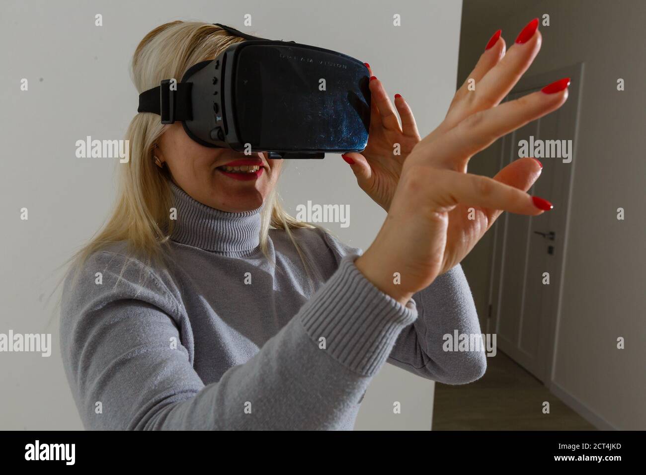 Future is now. Attractive young woman adjusting her VR headset and ...