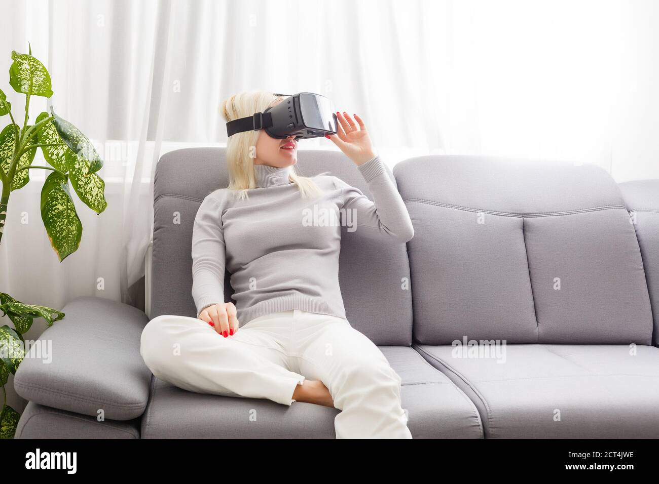 Future is now. Attractive young woman adjusting her VR headset and ...