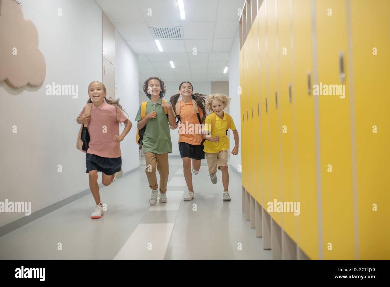 Happy schoolchildren running in the school corridor after lessons Stock ...