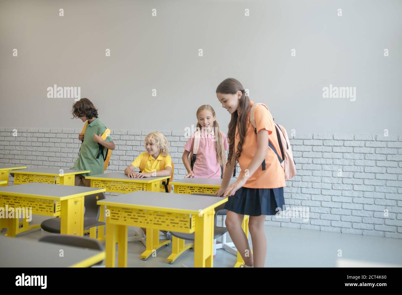 Four kids with backpacks entering the classroom and getting ready for ...