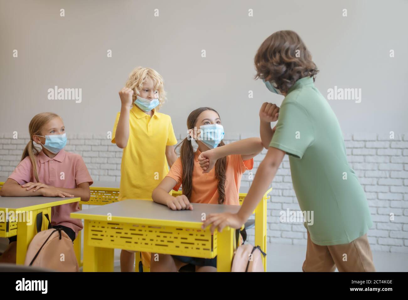 Classmates in masks greeting each other keeping social distancing Stock ...