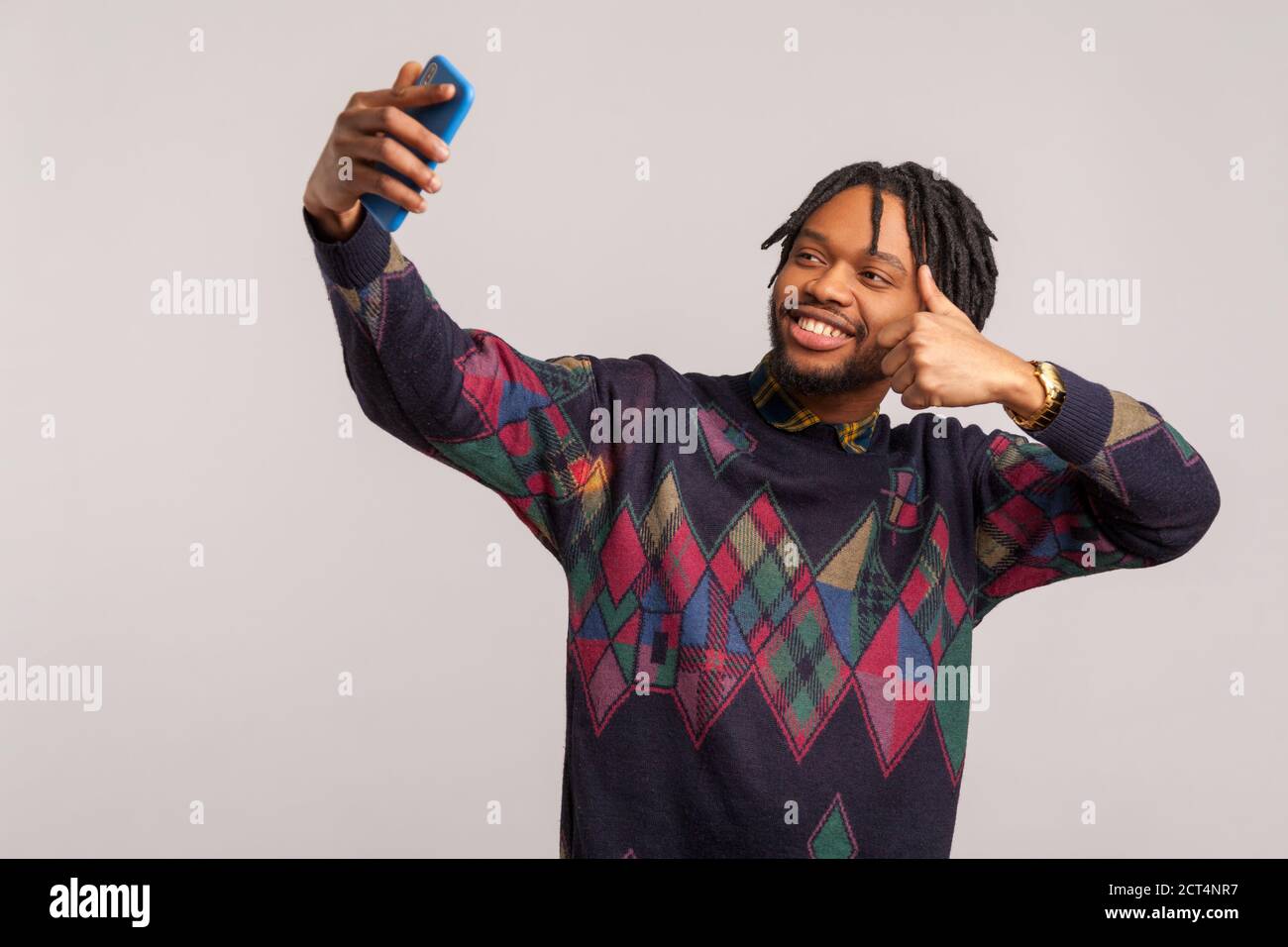 Satisfied smiling african man with dreadlocks and beard showing thumbs ...